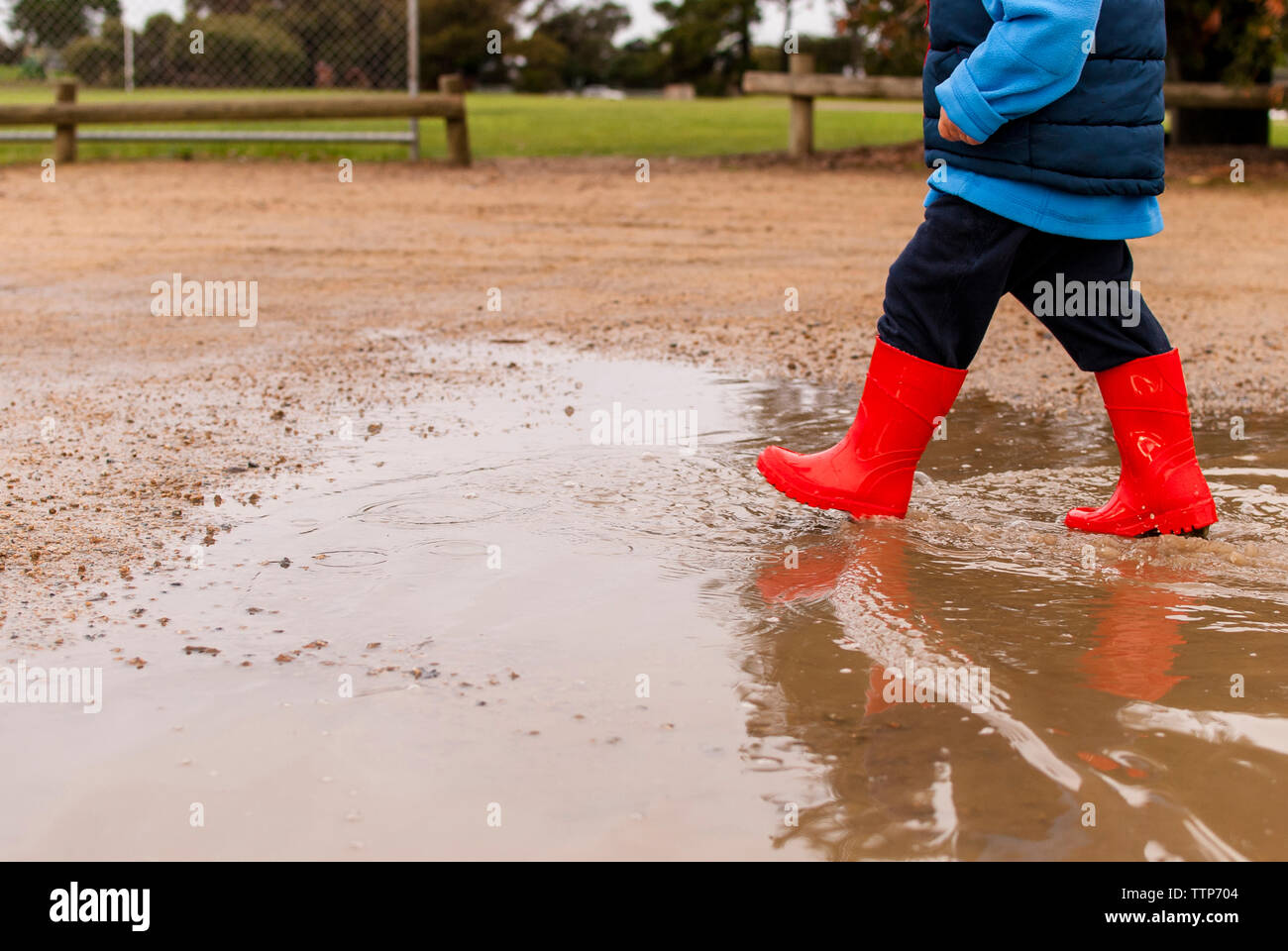 Low section of boy walking in puddle at playground Stock Photo - Alamy