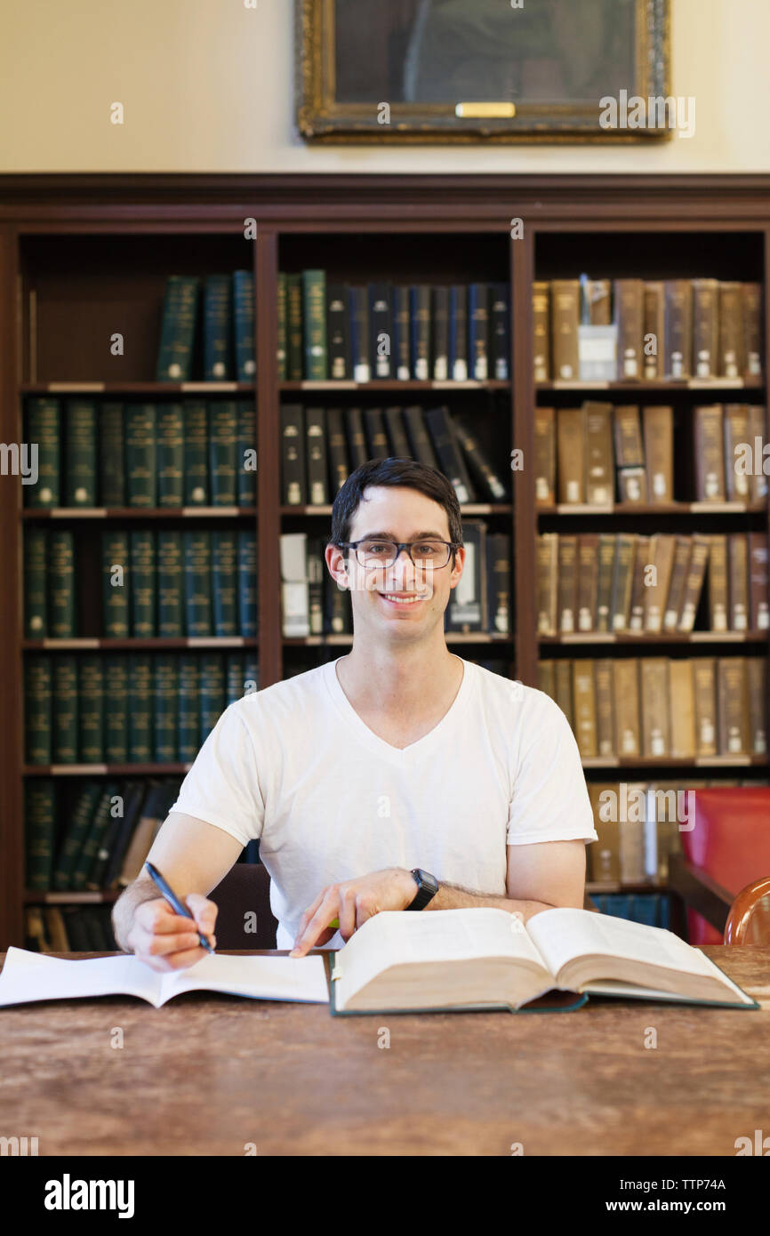 Portrait of confident smiling male student studying in library Stock ...