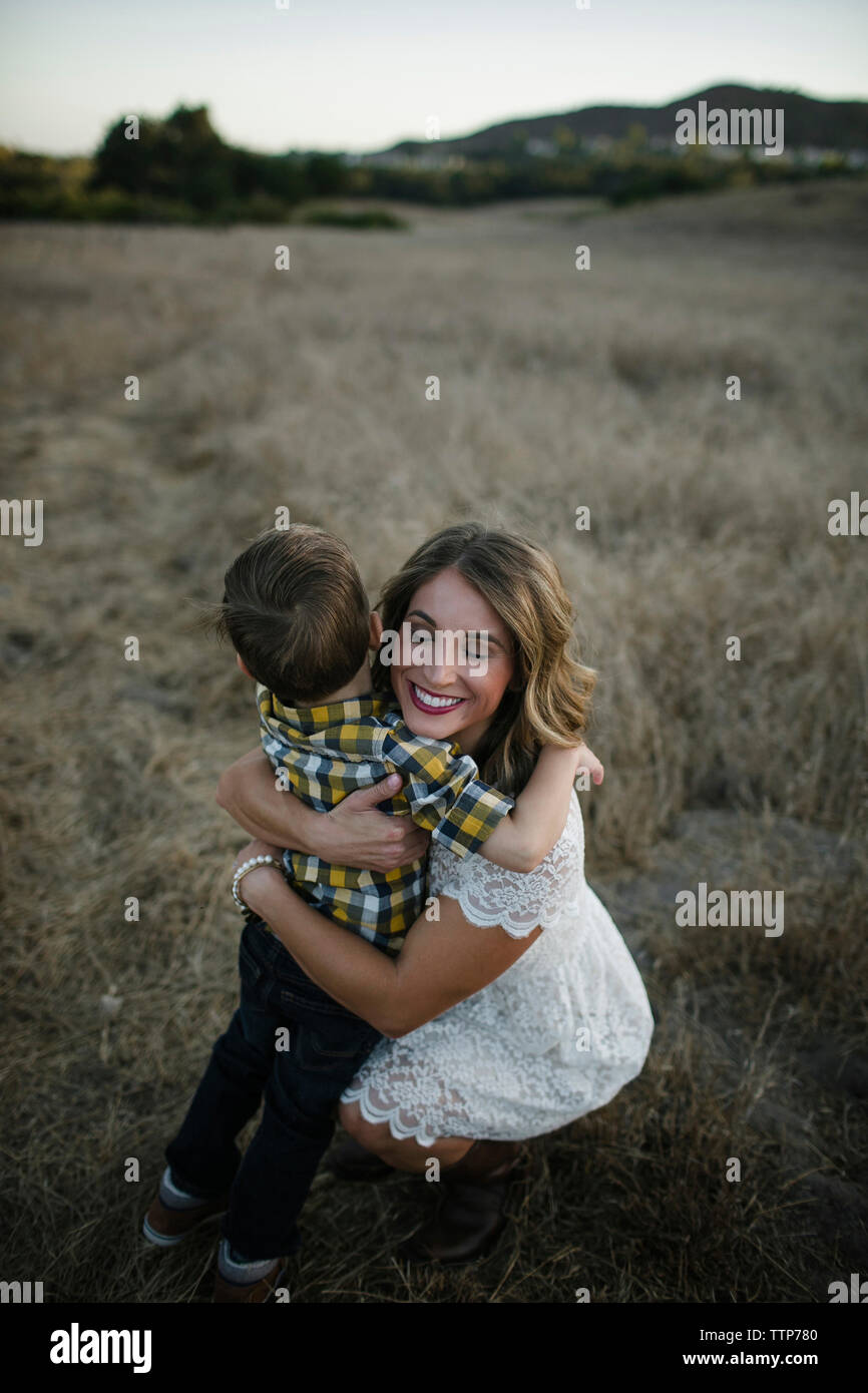 High angle view of mother embracing son while crouching on field Stock ...