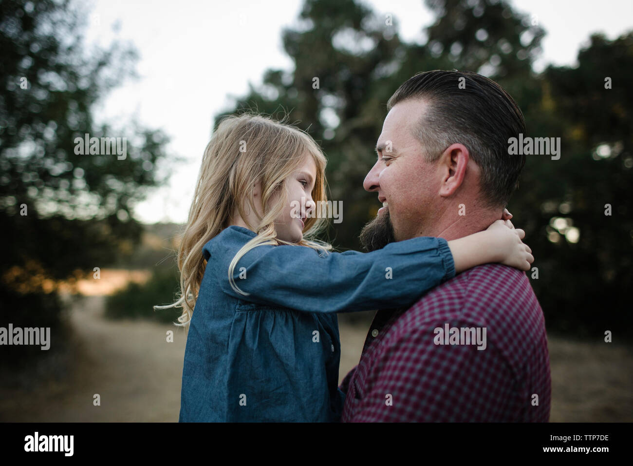 Side view of father and daughter looking at each other on field Stock ...