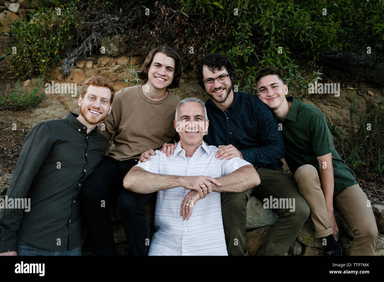 Portrait of happy father standing by sons against plants at park Stock ...