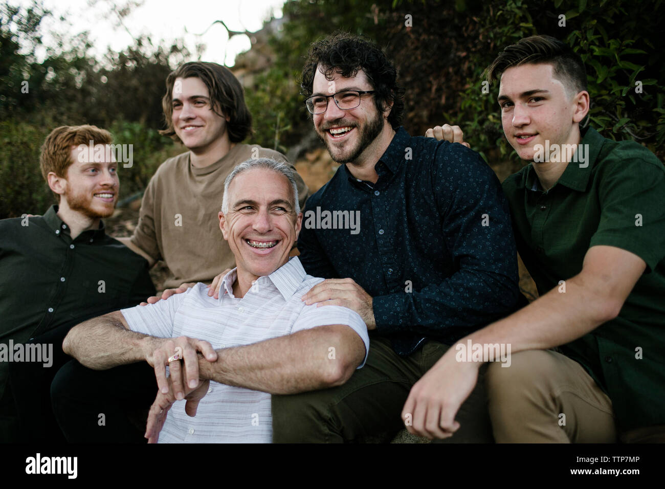 Happy father standing by sons against plants at park Stock Photo - Alamy