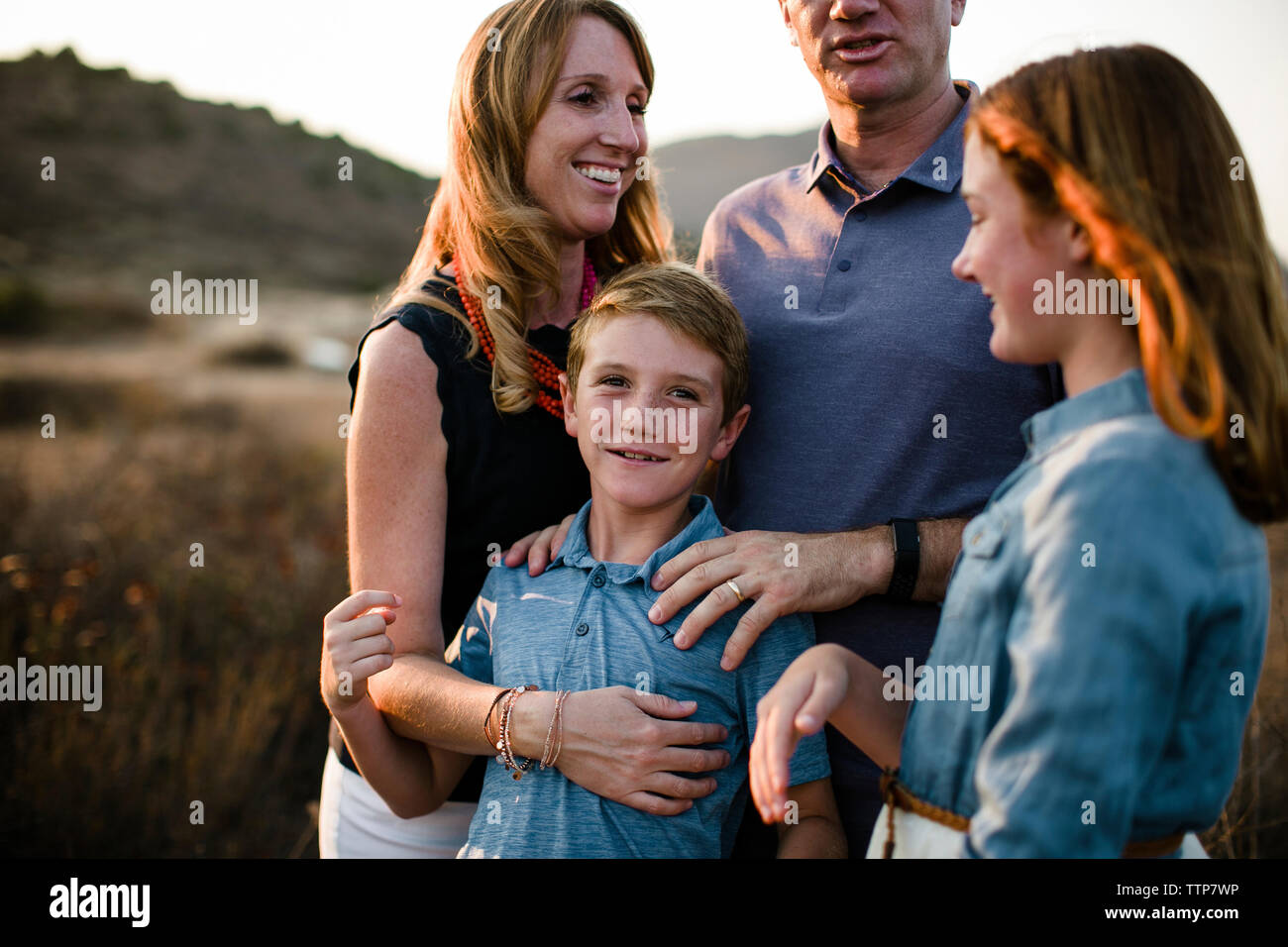 Happy loving family standing together on field during sunset Stock ...