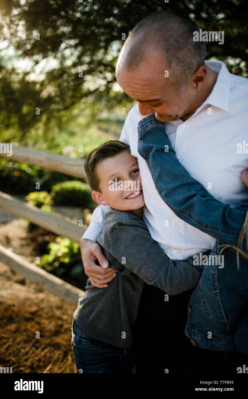 Son Giving Dad Hugs While Dad Looks On in SoCal Stock Photo - Alamy