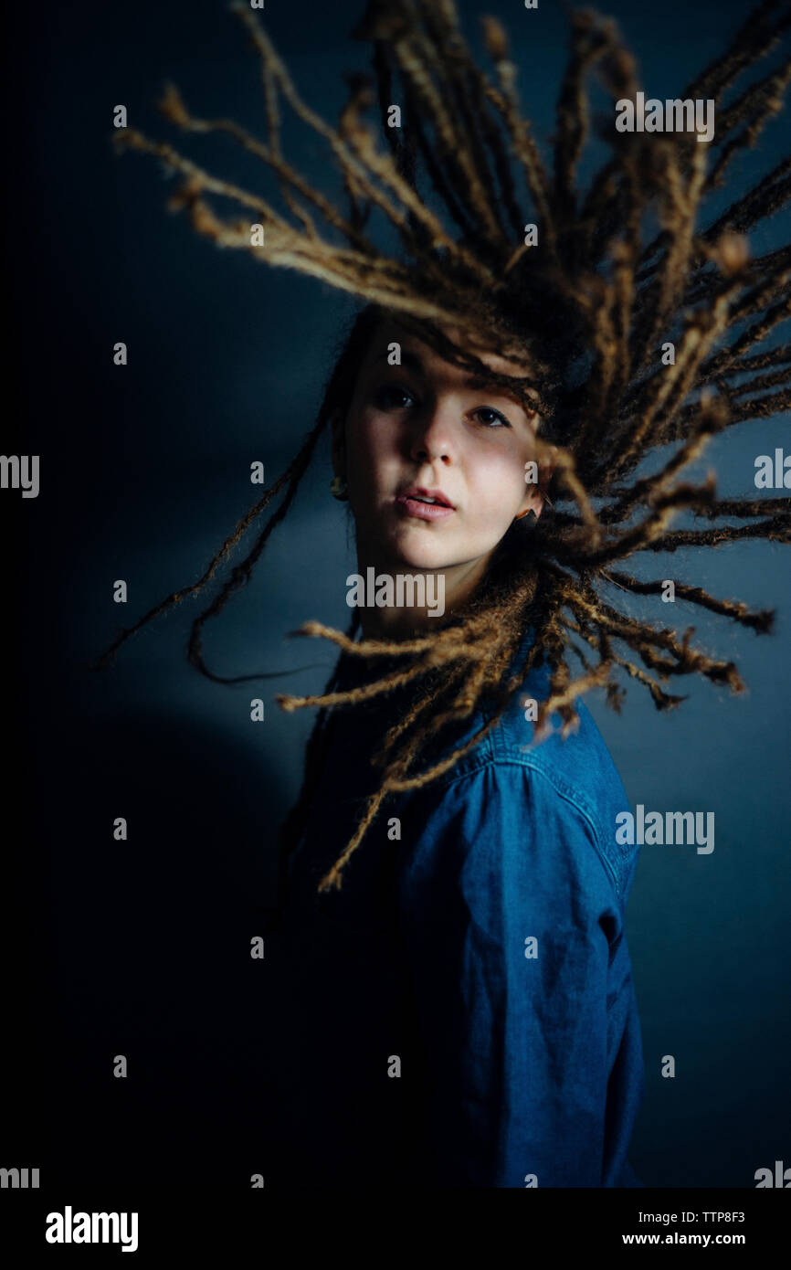 Portrait of confident fashion model tossing hair against blue ...