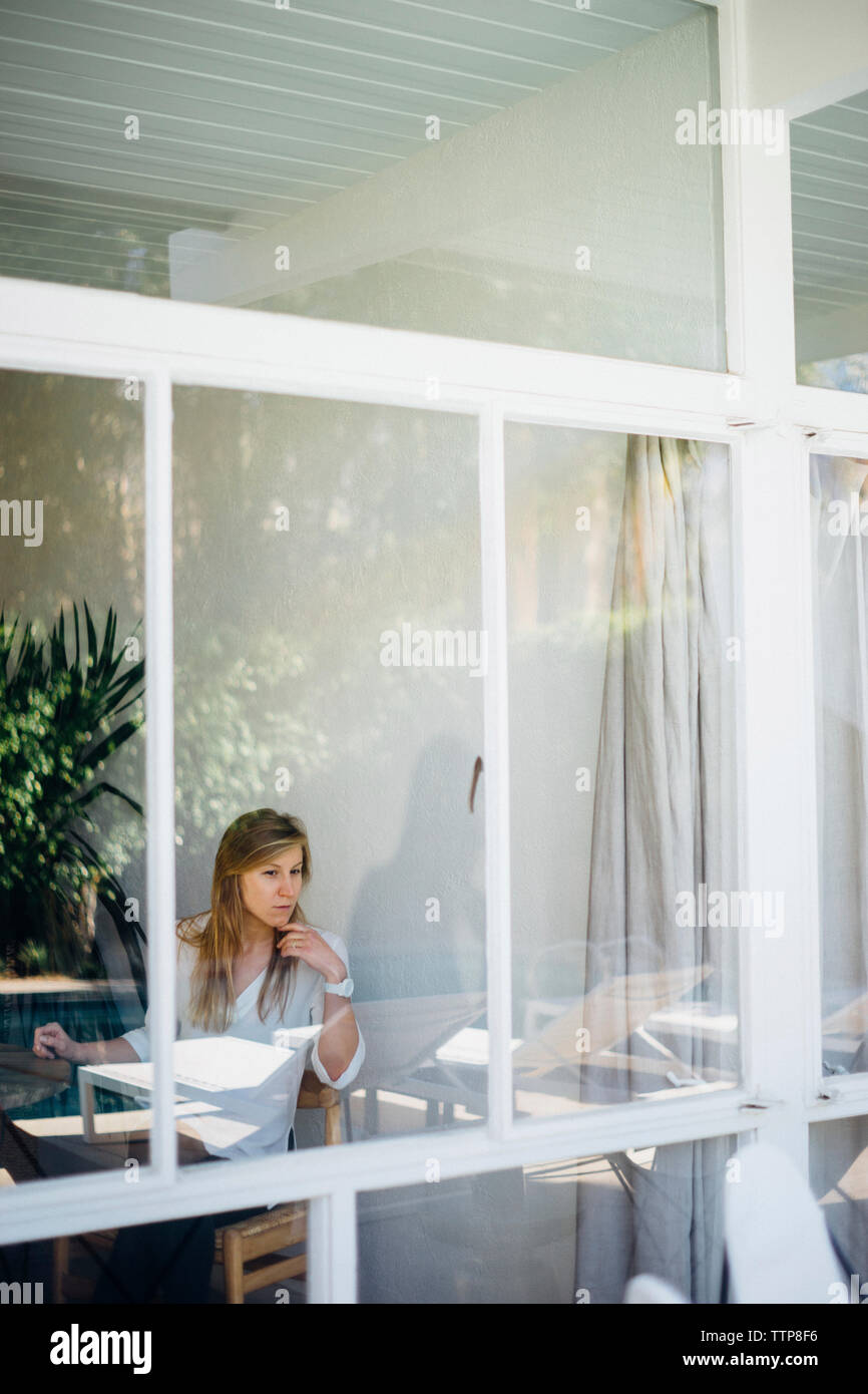 Thoughtful woman looking through window Stock Photo - Alamy