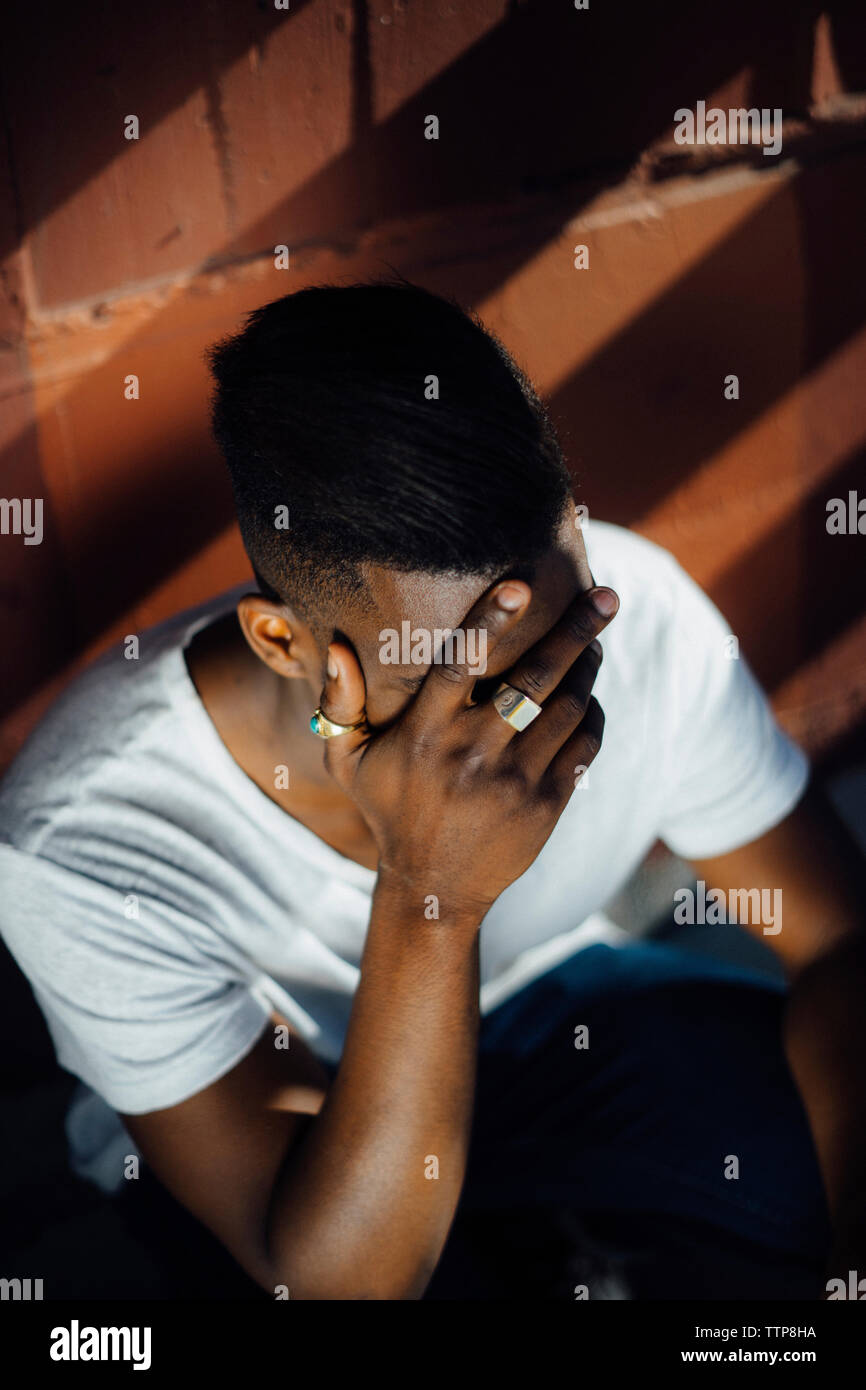 High angle view of sad man sitting against wall Stock Photo - Alamy
