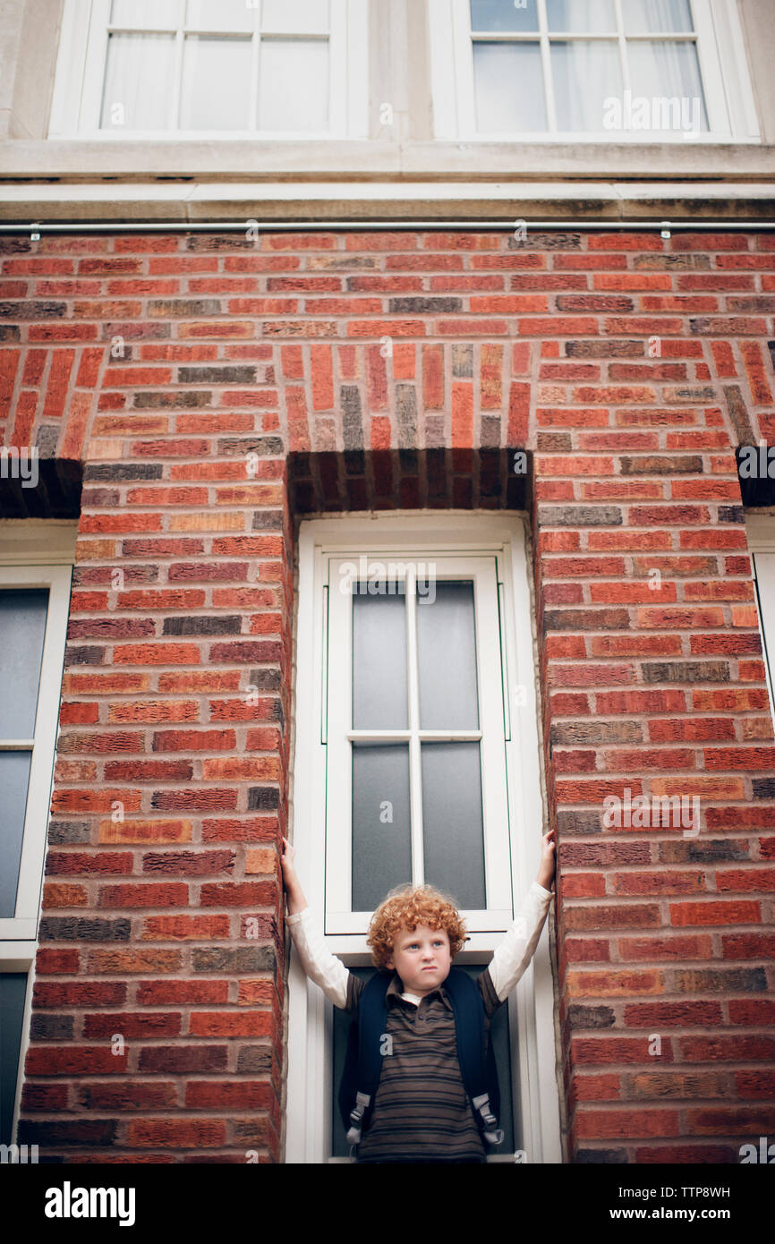 Boy standing against window of school building Stock Photo - Alamy