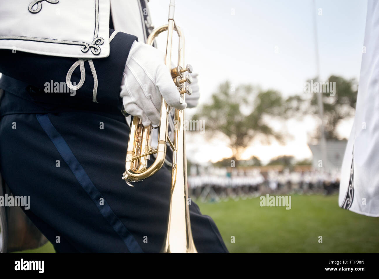 Midsection of person holding trumpet at field Stock Photo - Alamy