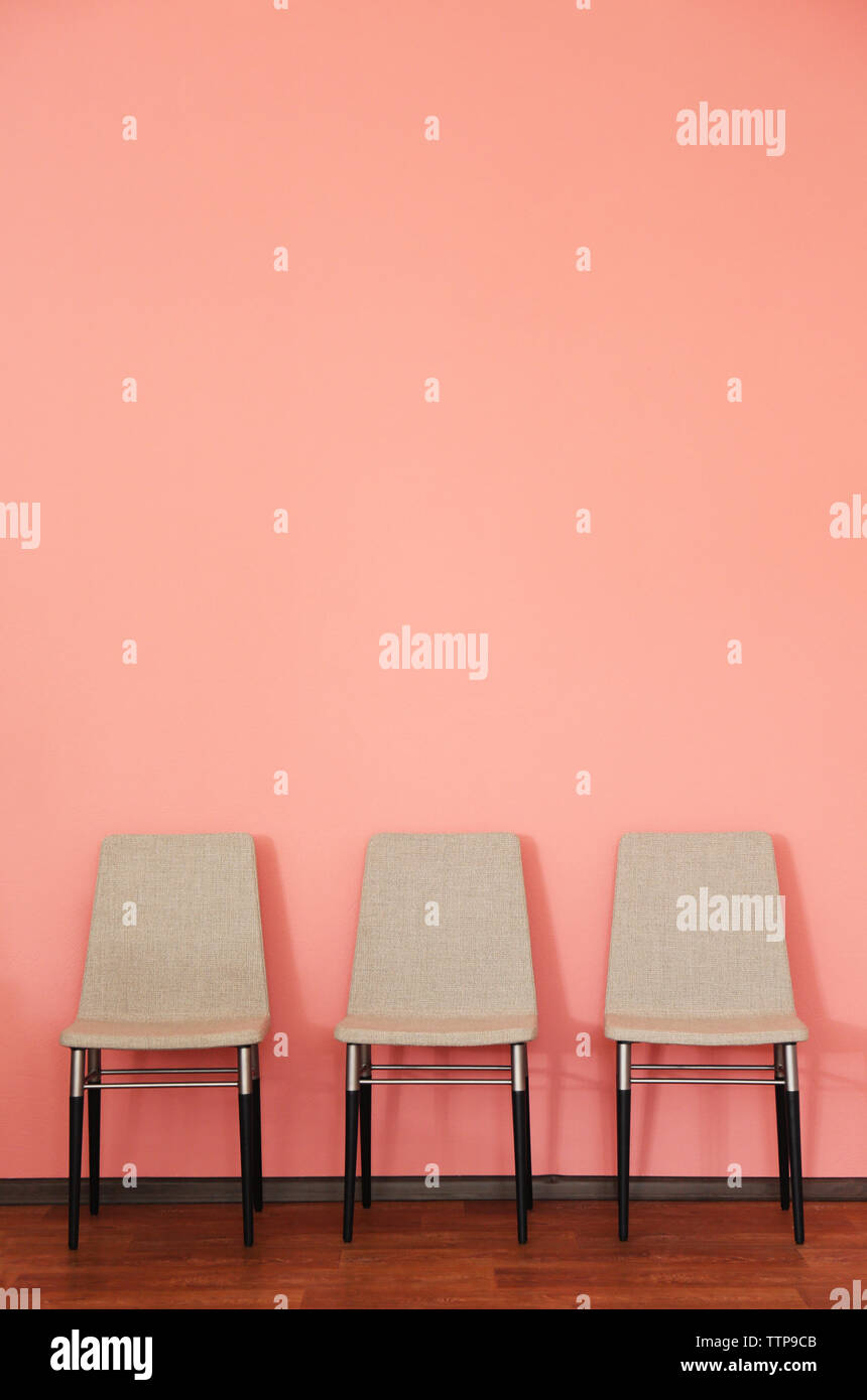 Three modern chairs on wall background Stock Photo - Alamy