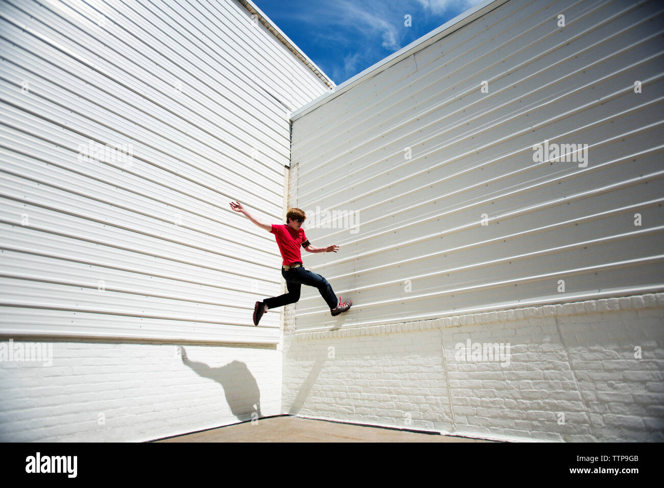 Low angle view of man jumping on white wall Stock Photo - Alamy