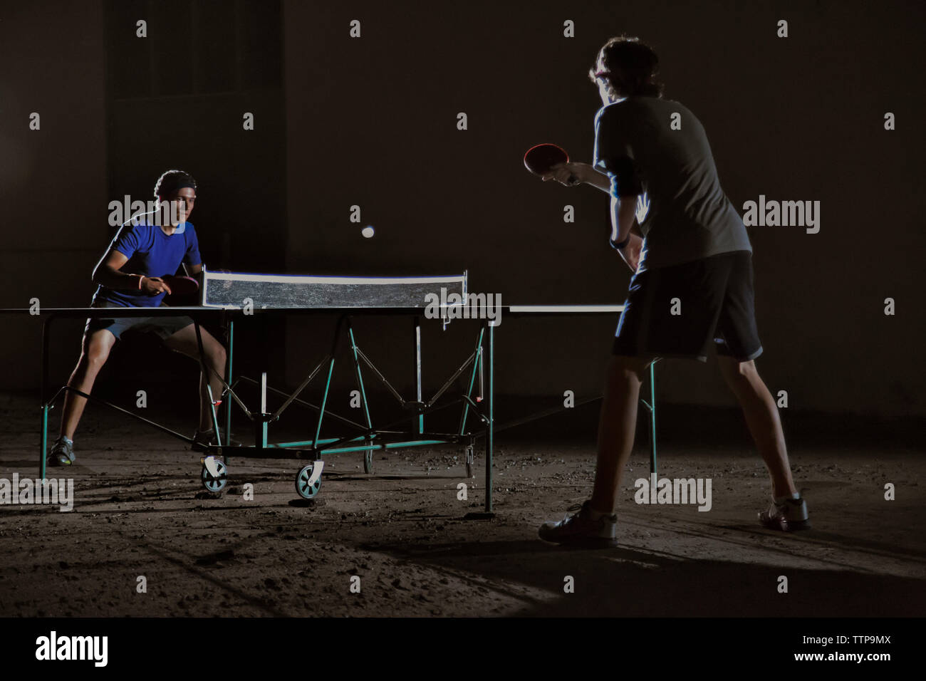 Friends playing table tennis against building at night Stock Photo - Alamy