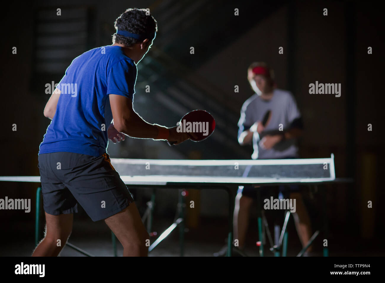Friends playing table tennis against illuminated building Stock Photo ...