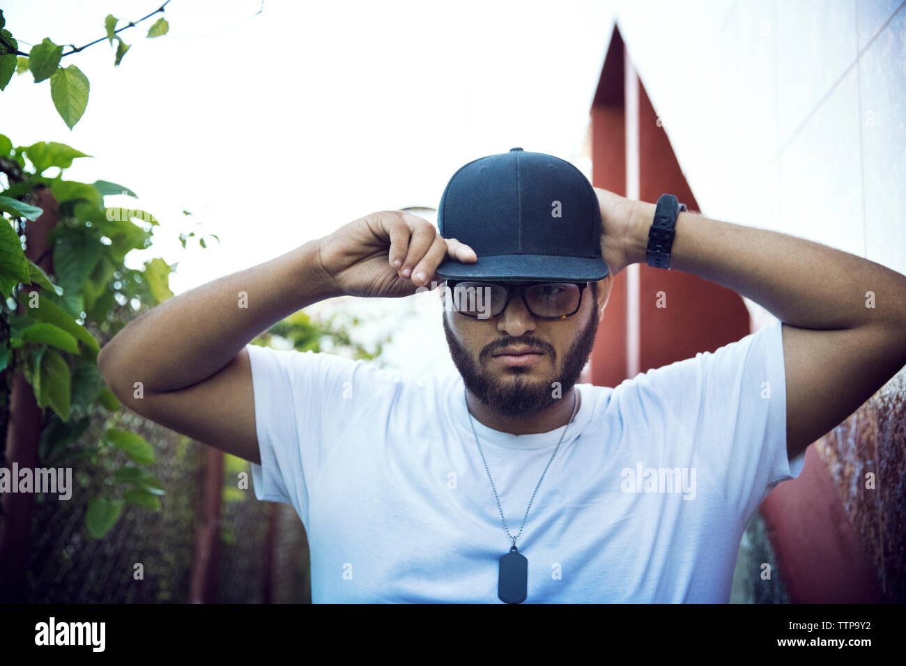 Portrait of man wearing cap while standing on walkway Stock Photo - Alamy