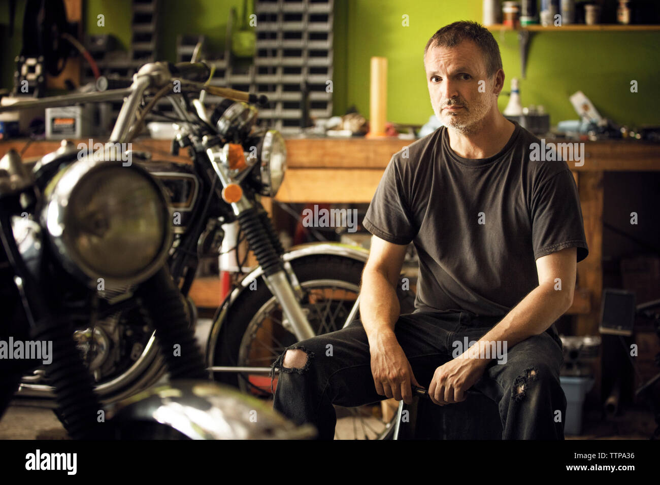 Portrait of owner sitting on stool in store Stock Photo - Alamy