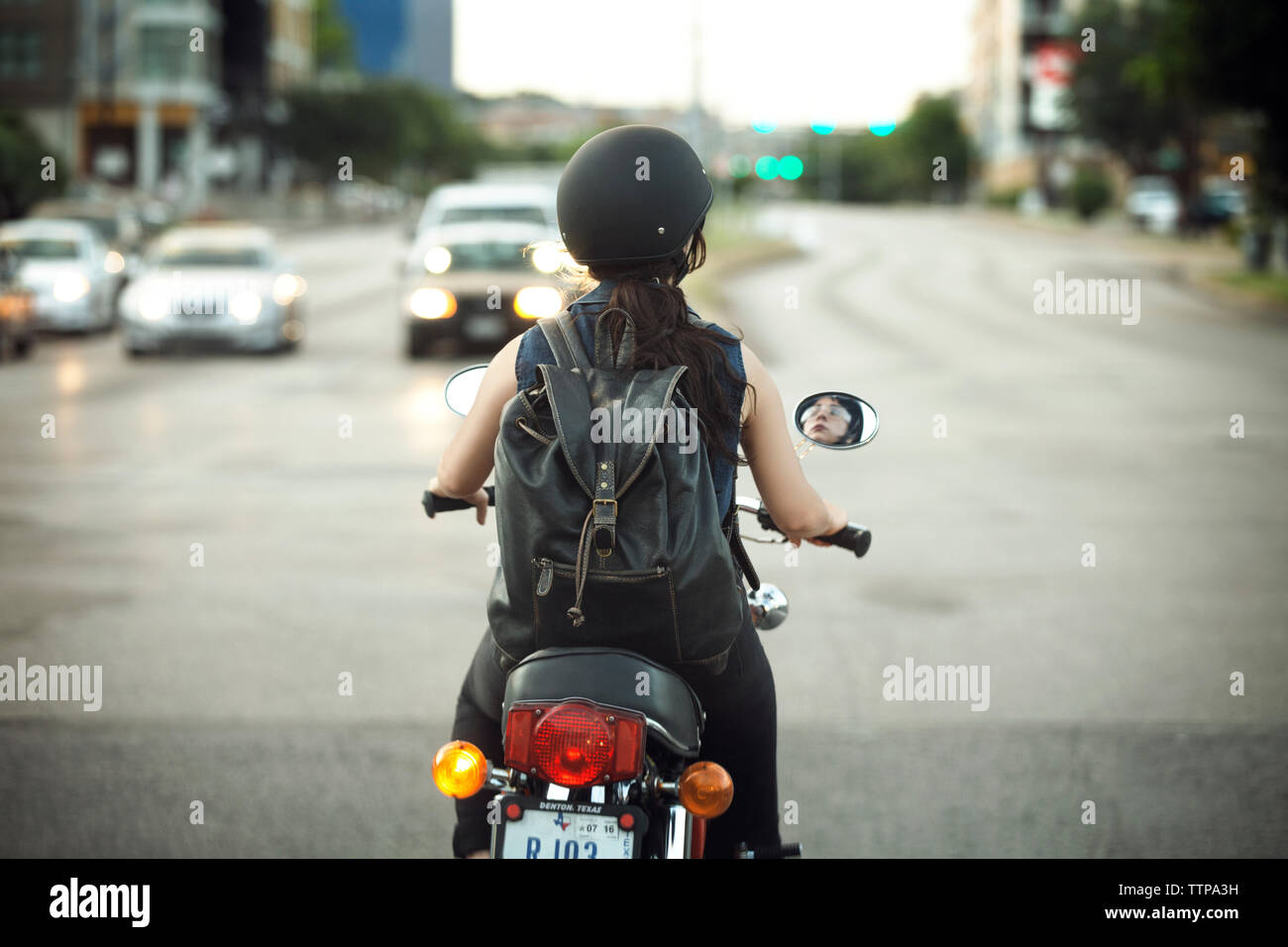 Rear view of woman with backpack riding motorcycle on road Stock Photo ...
