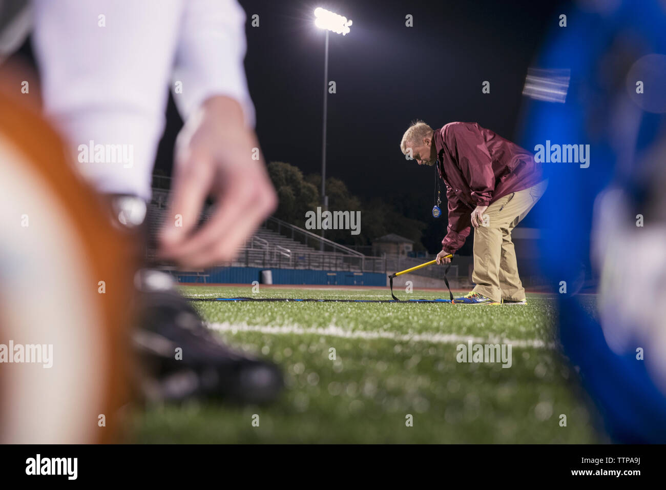 American football coach placing agility ladder on turf at stadium Stock ...