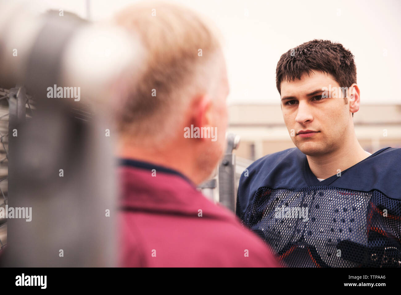Coach discussing with American football player at stadium Stock Photo ...