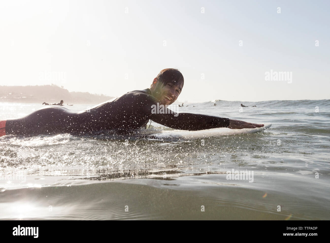 Side view portrait of happy male surfer lying on surfboard in sea ...