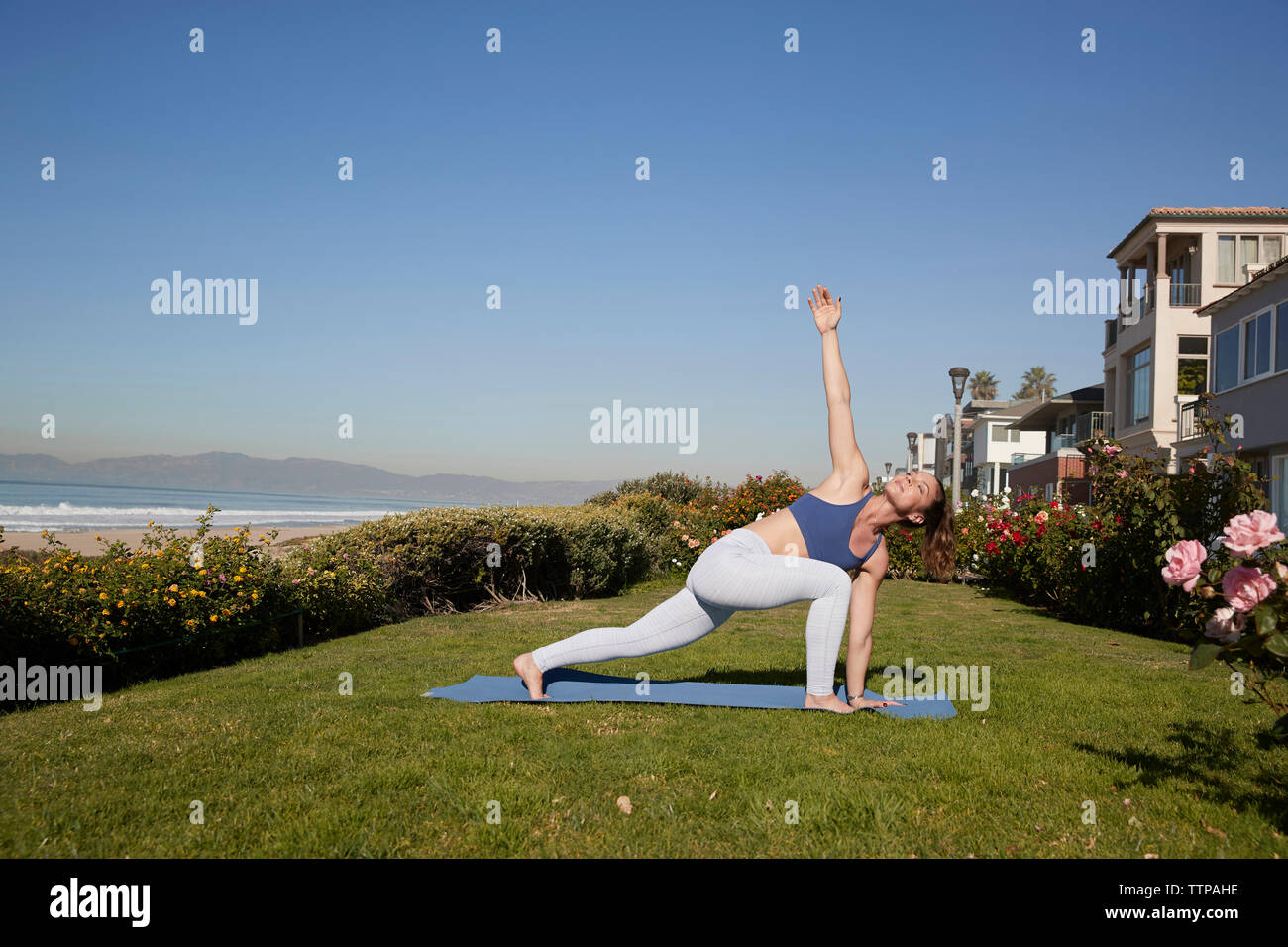 Full length of woman with legs apart and arms outstretched practicing ...