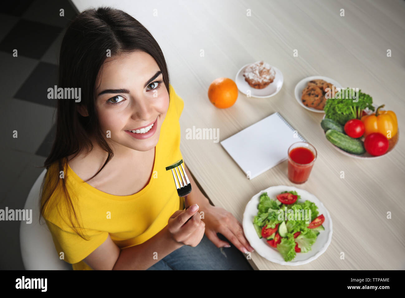 Healthy food concept. Young woman sitting at kitchen table Stock Photo ...