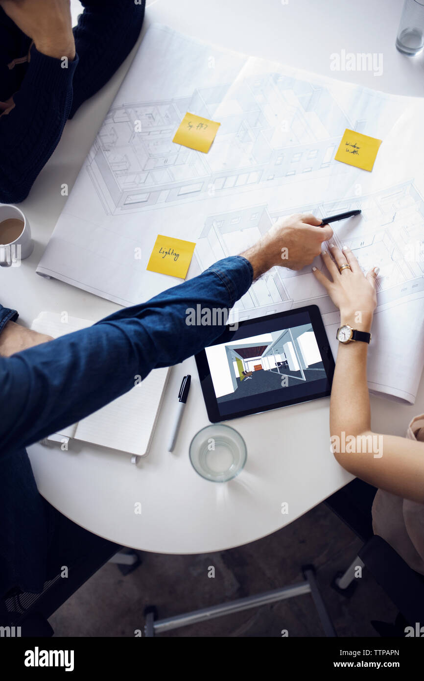 Overhead view of architects discussing blueprints at creative office ...
