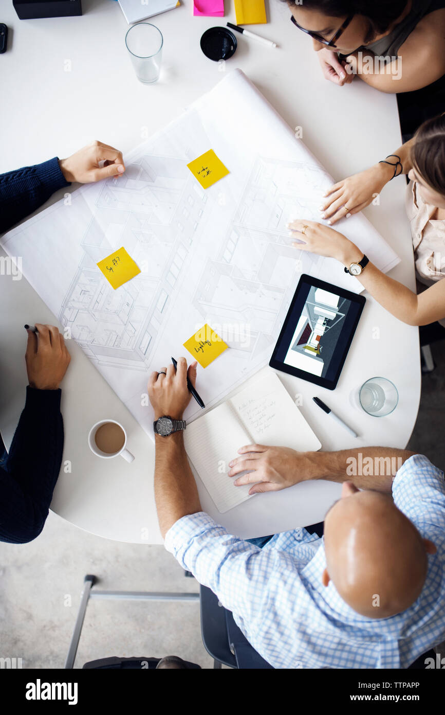 Overhead view of architects discussing over blueprints at creative ...