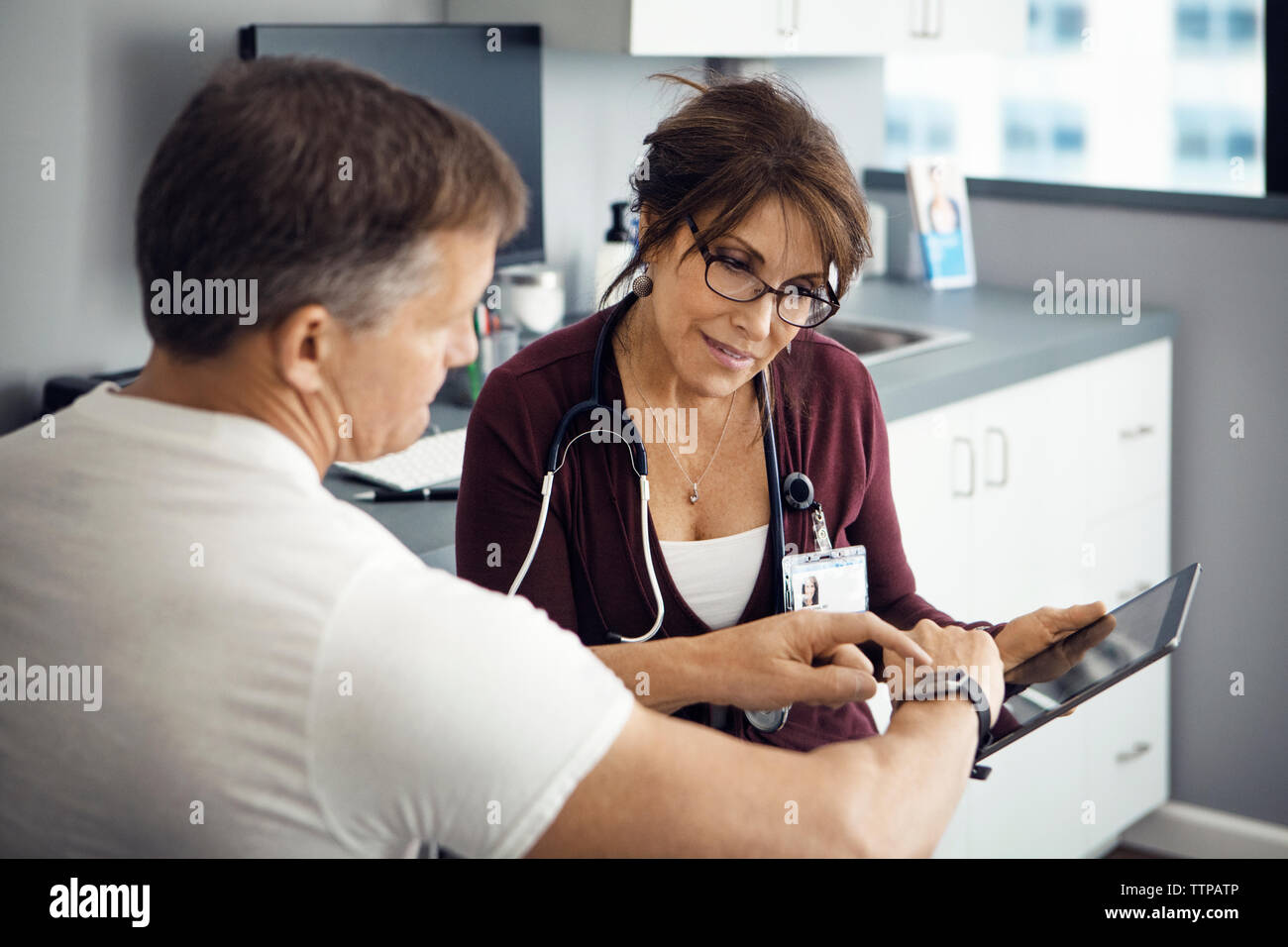 Male patient pointing at wrist watch while discussing with female ...