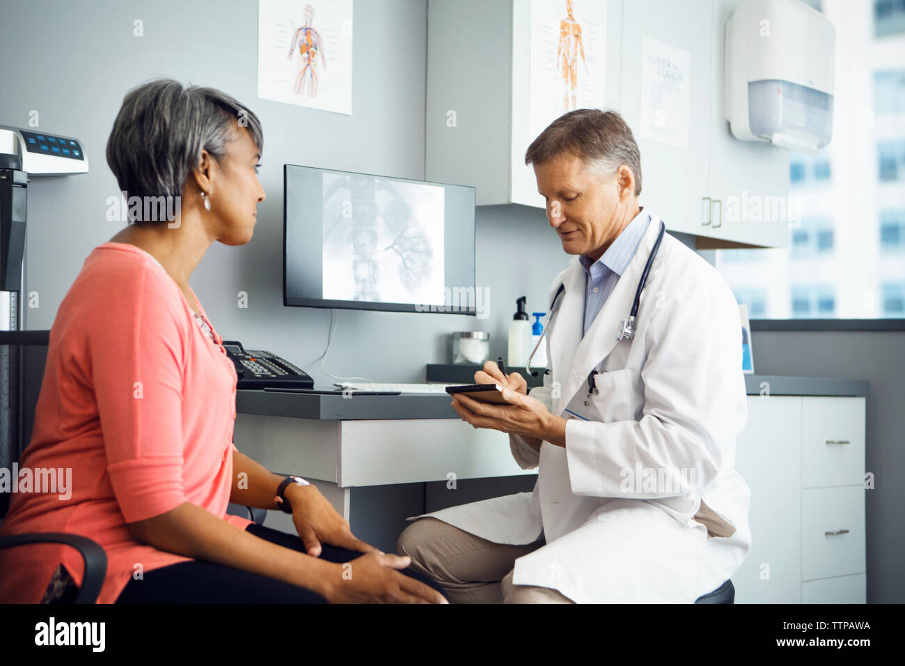 Male doctor writing prescription for female patient in clinic Stock ...