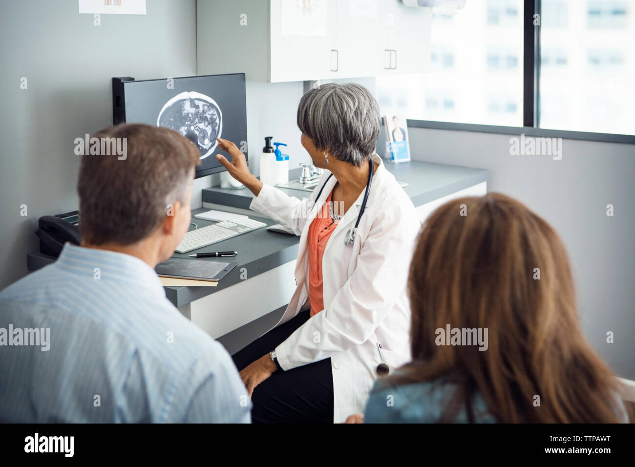 Female doctor explaining report to couple in clinic Stock Photo - Alamy
