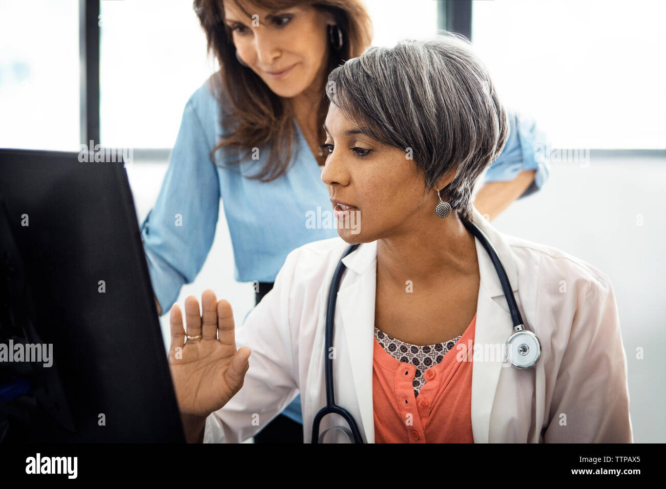 Female doctor explaining report on computer to patients in clinic Stock ...