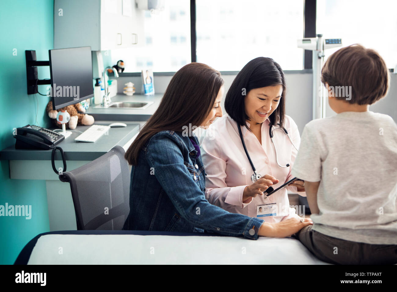 Female doctor using tablet computer with family in clinic Stock Photo ...