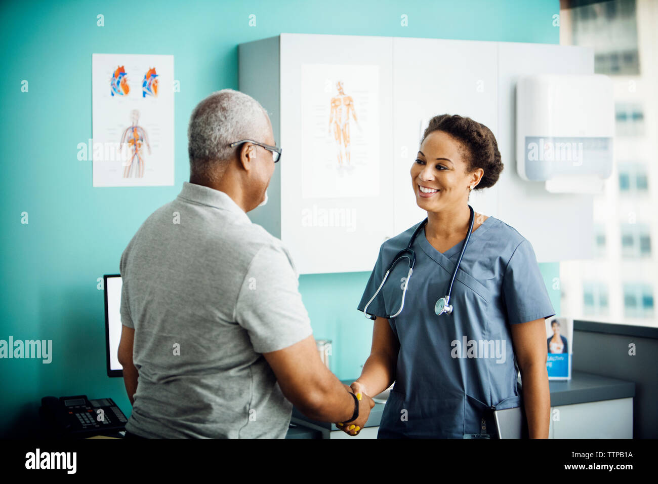 Happy female doctor greeting senior male patient in clinic Stock Photo ...