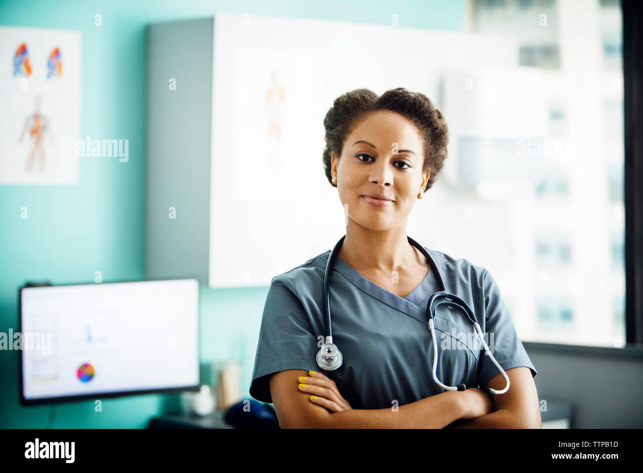 Portrait of confident female doctor standing arms crossed in clinic ...