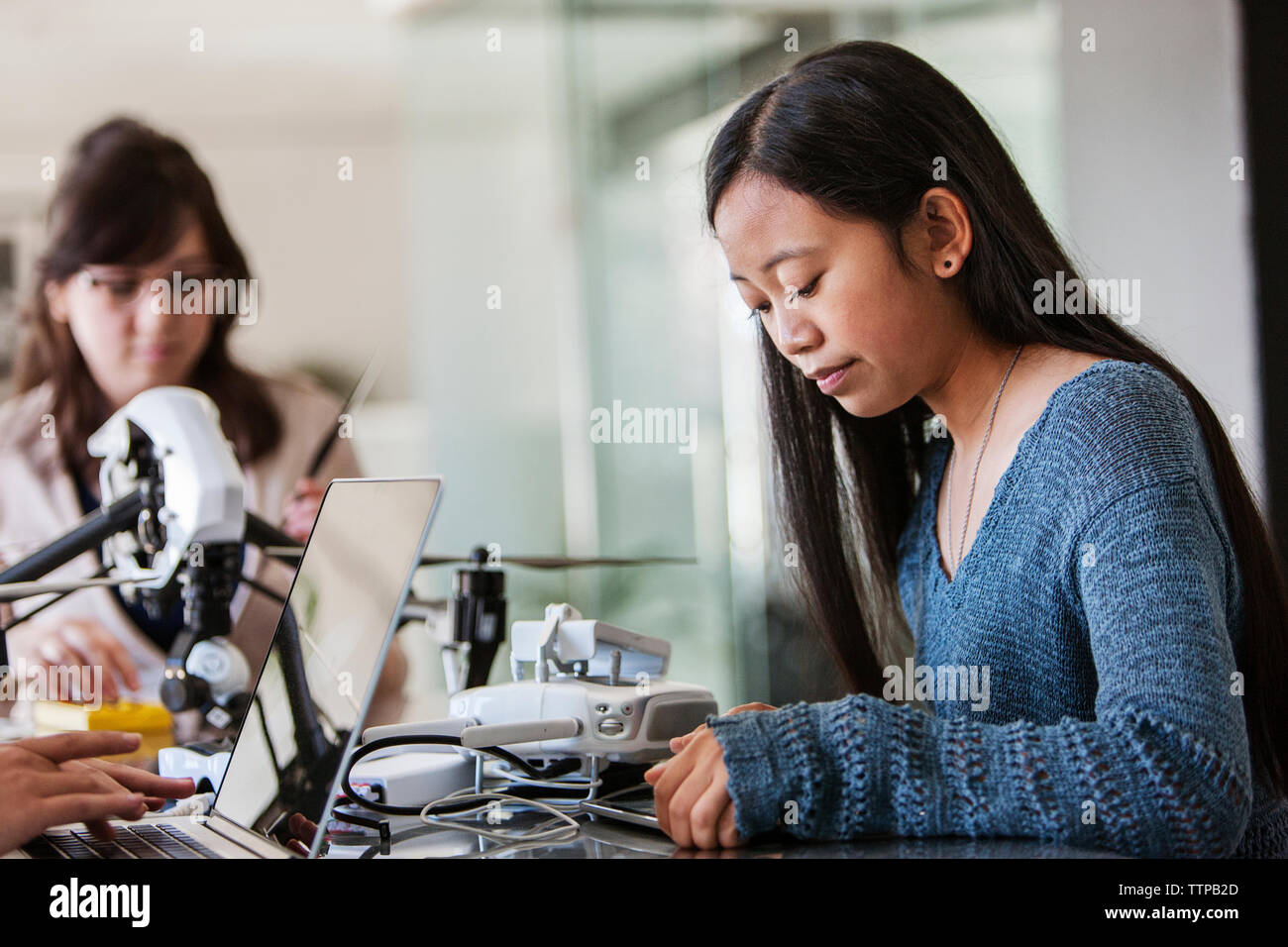 Concentrated female student using tablet computer while sitting with ...