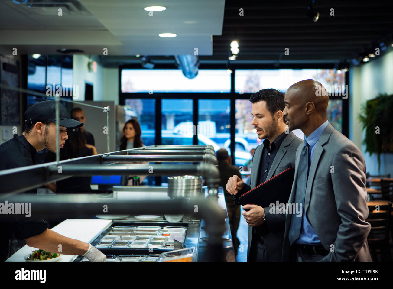 business people ordering food while standing by counter in restaurant ...