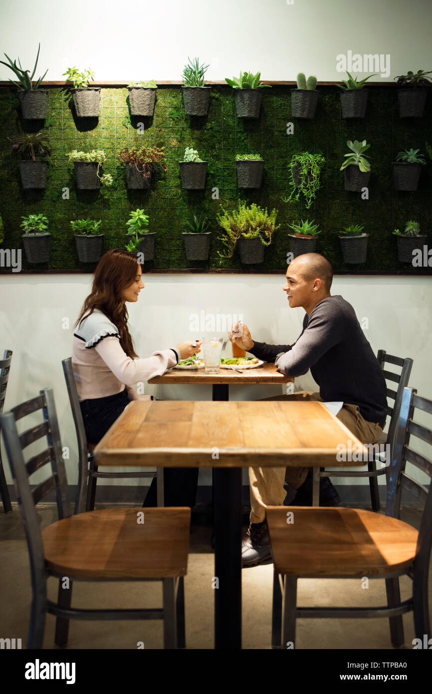 Side view of couple talking while having food in restaurant Stock Photo ...