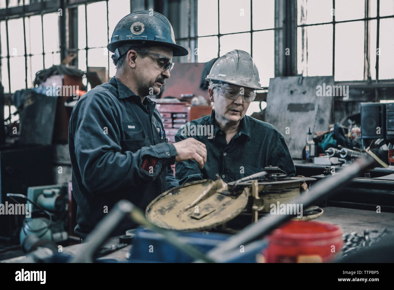 Coworkers working at table in metal industry Stock Photo - Alamy
