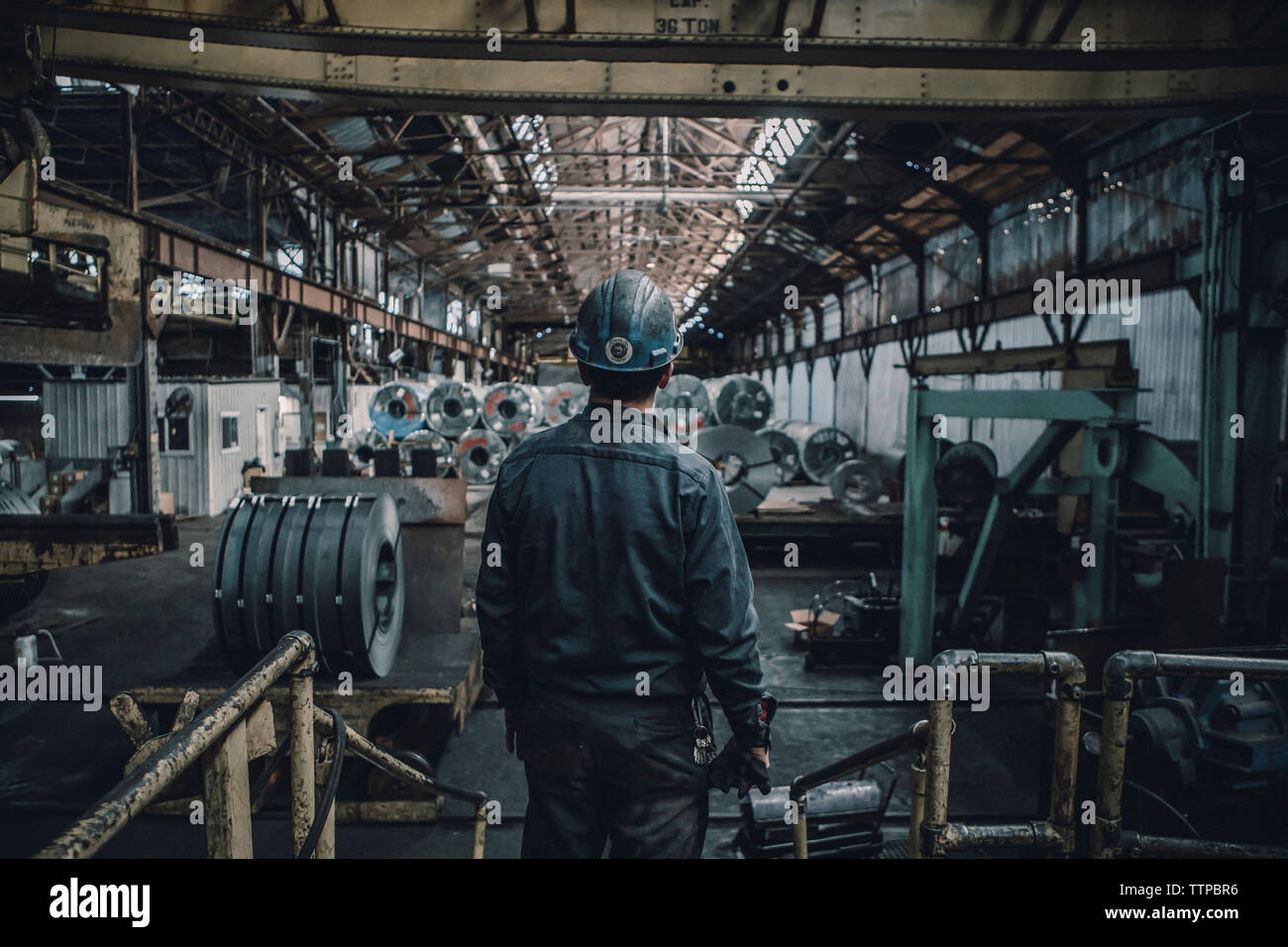 Rear view of male worker standing in factory Stock Photo - Alamy