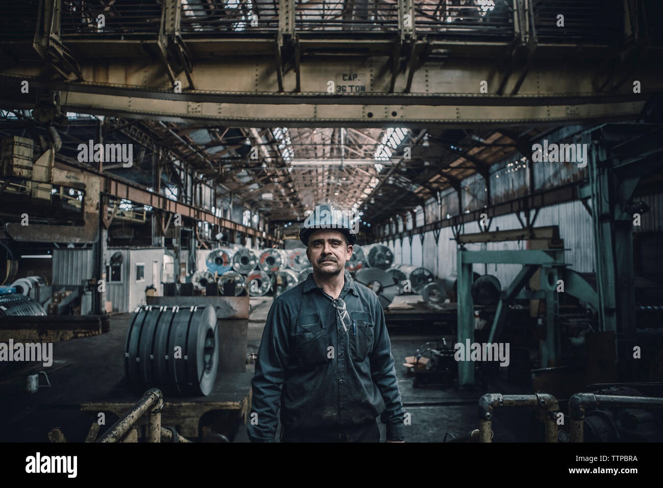 Portrait of confident male worker standing against steel sheets in ...