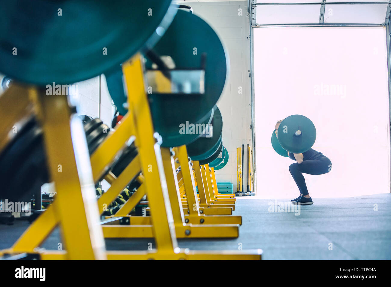 Side view of woman lifting barbell in gym Stock Photo - Alamy
