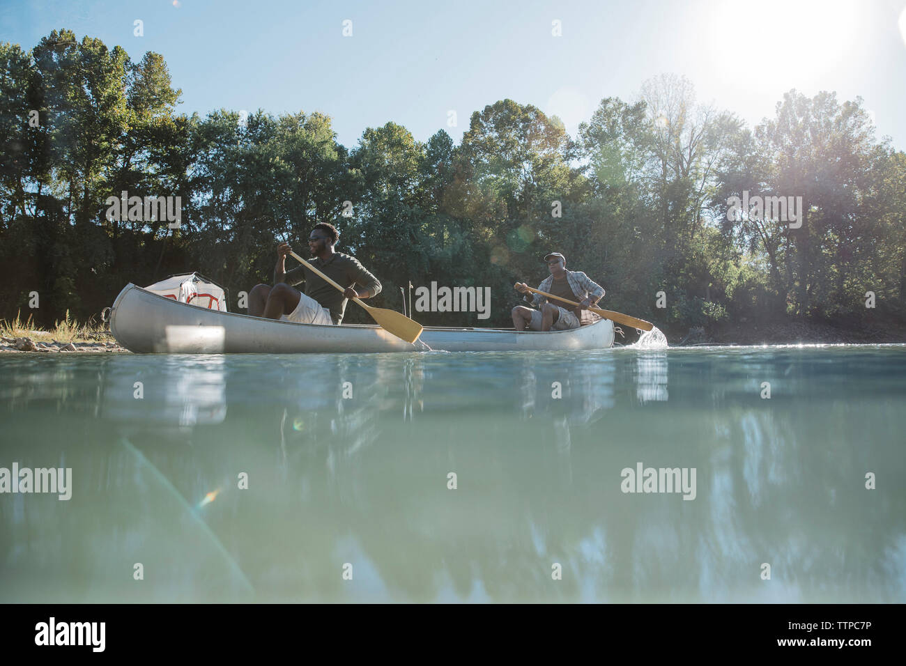 Water surface of male friends rowing on lake against sky Stock Photo ...