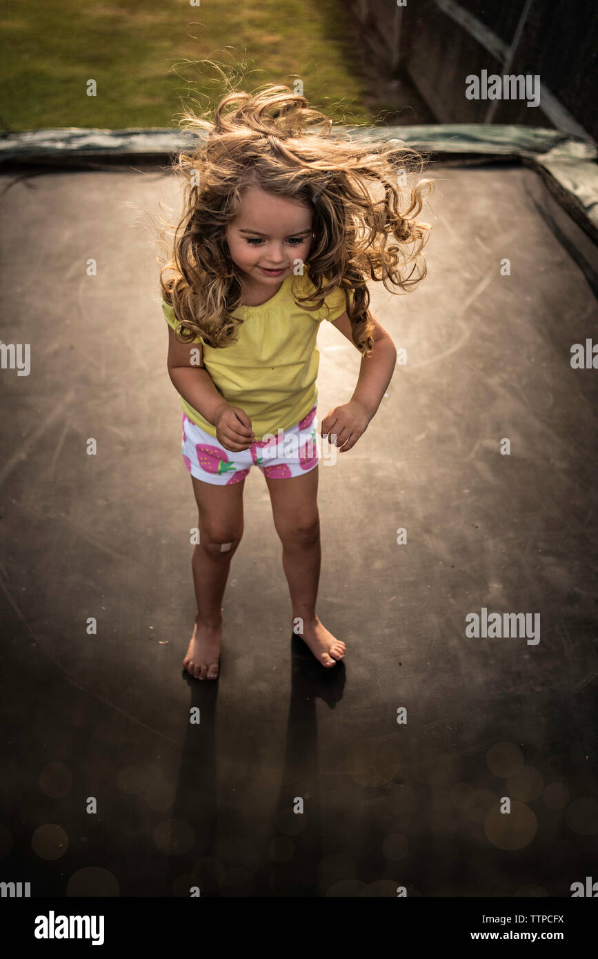 High angle view of playful girl standing on trampoline Stock Photo - Alamy