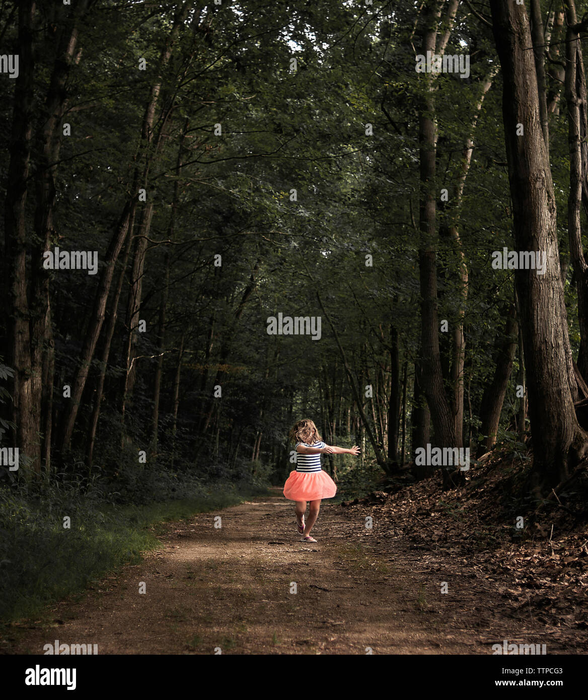 Girl dancing on dirt road amidst forest Stock Photo - Alamy