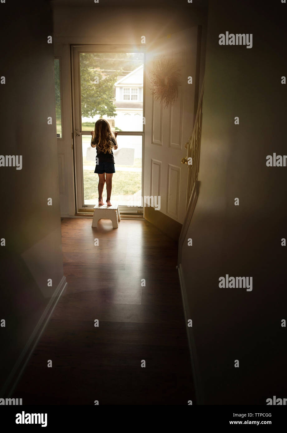 Rear view of girl standing by door at home Stock Photo - Alamy