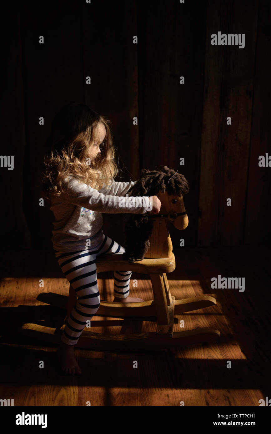 Side view of girl sitting on rocking horse at home Stock Photo - Alamy