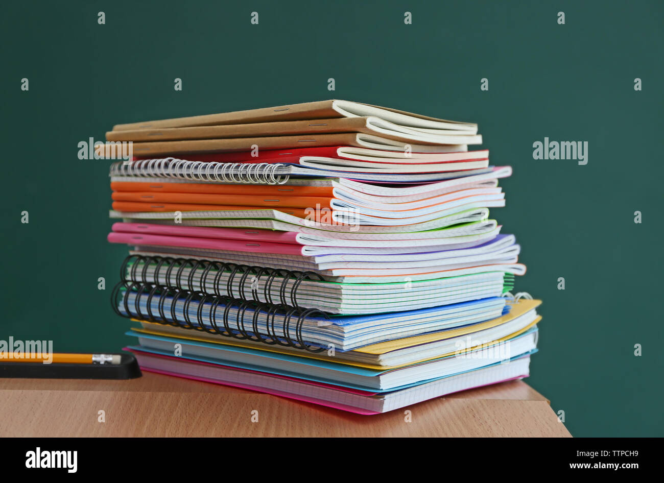 Stacked school notebooks on blackboard background Stock Photo - Alamy