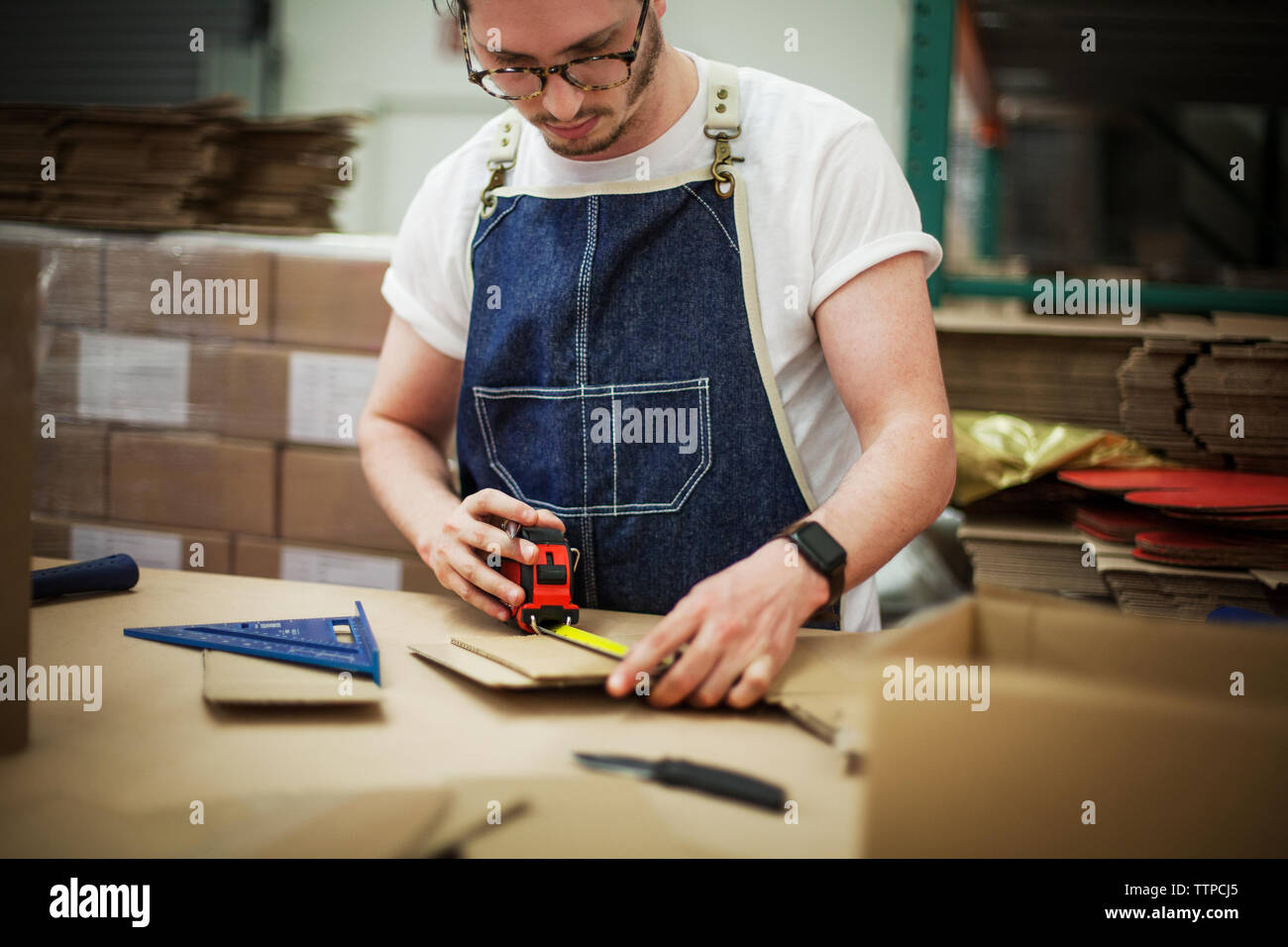 Midsection of male worker measuring cardboard in warehouse Stock Photo ...