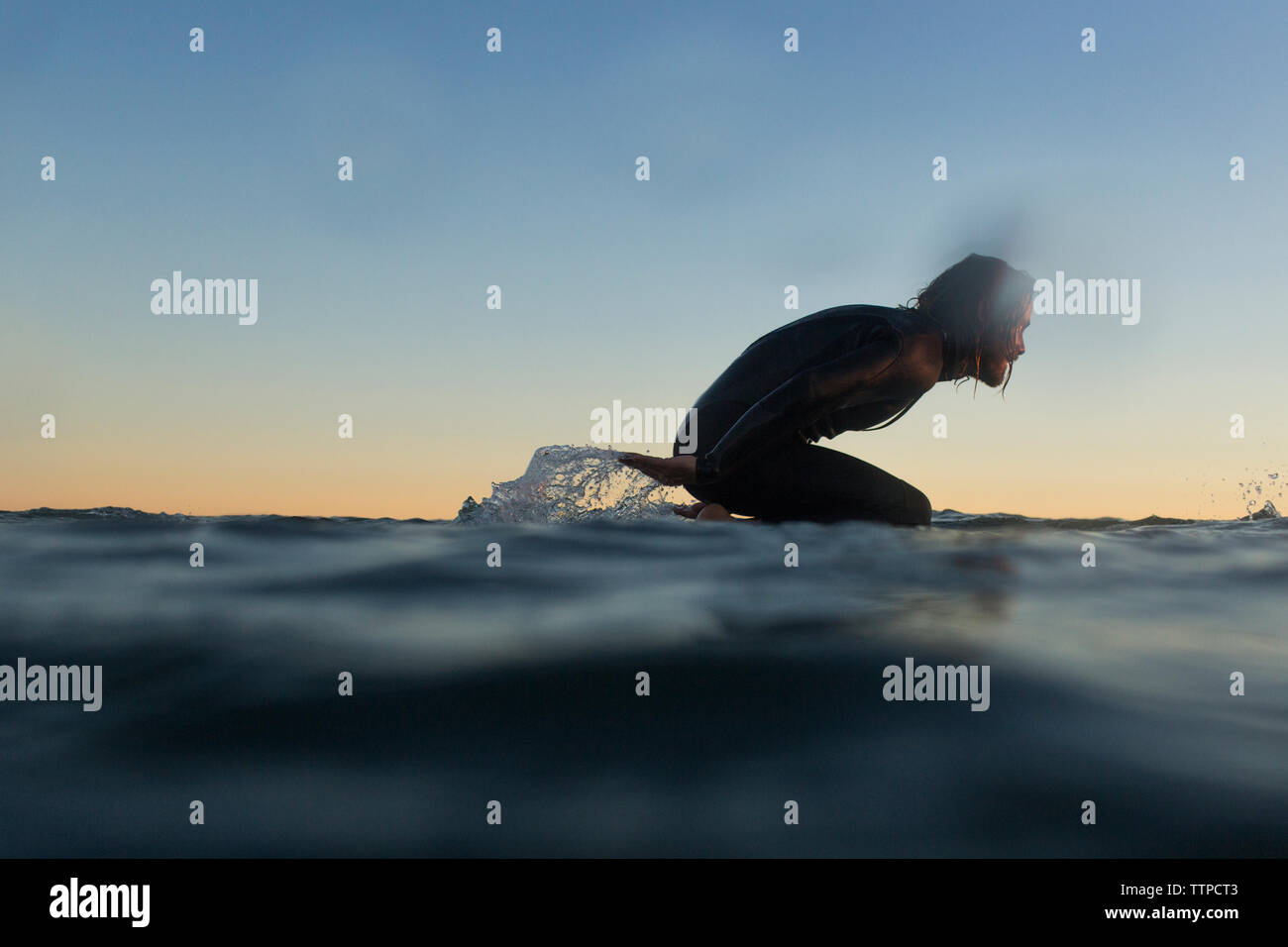 Side view of confident man surfing on sea during sunset Stock Photo - Alamy