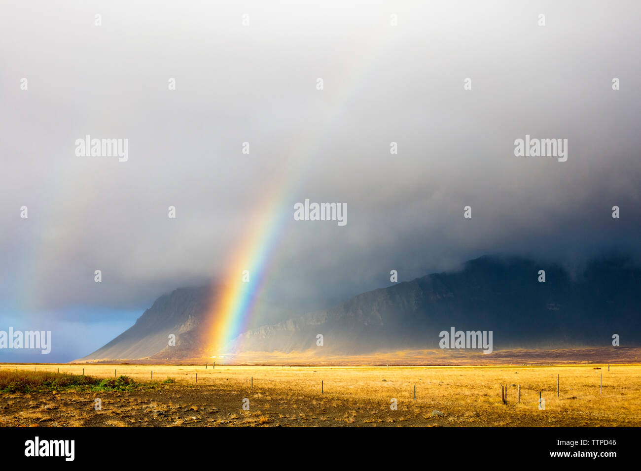 Majestic view of rainbow over landscape amidst cloudy sky Stock Photo ...